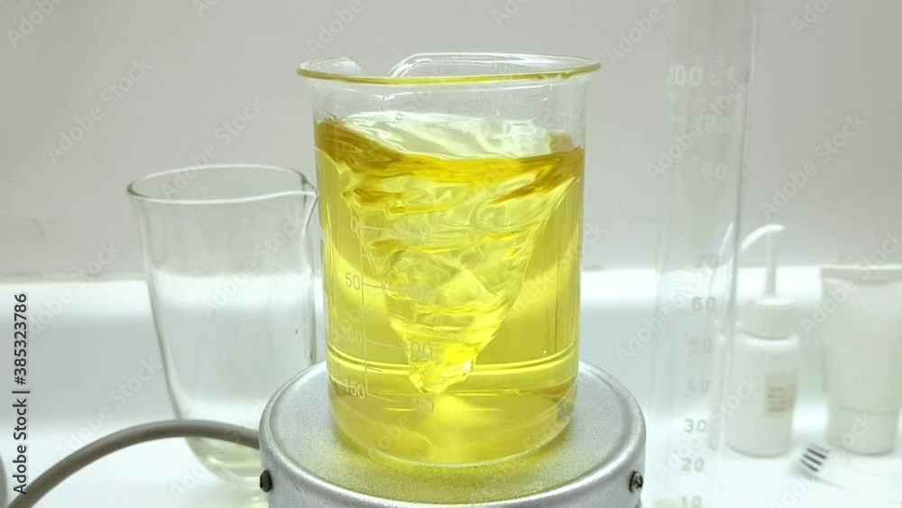 yellow chemical solution spinning in beaker on magnetic stirrer, close ...