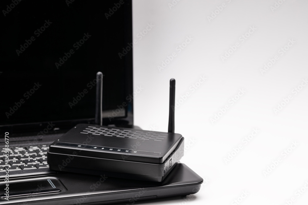 black wifi router and laptop over white background. online and network ...