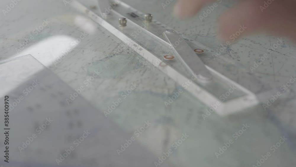 A captain is using a ruler to measure and calculate a navigation route ...