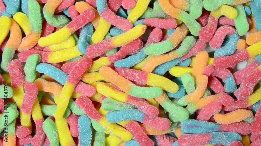 HD video zooming out from many colorful gummy worms coated in sugar ...