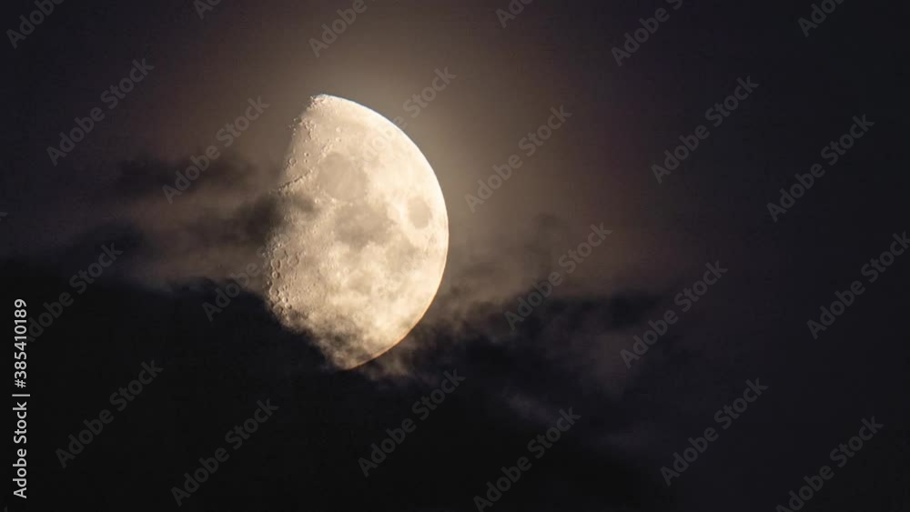 The half-moon bright in the night sky pouring orange glow in the space ...