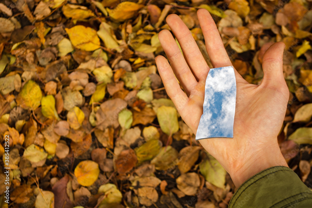 holding broken mirror splinter on hand palm which reflects blue sky ...