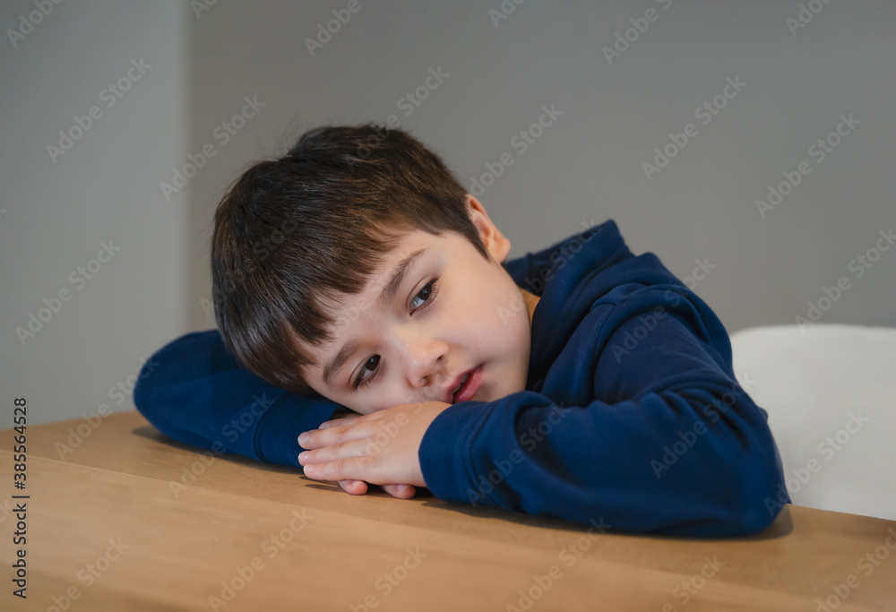 Foto de Portrait tired kid lying head down on his arm lookig out deep ...