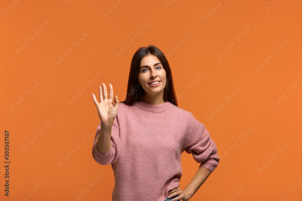 Hi to all. Friendly-looking polite woman saying hi, waving his hand ...