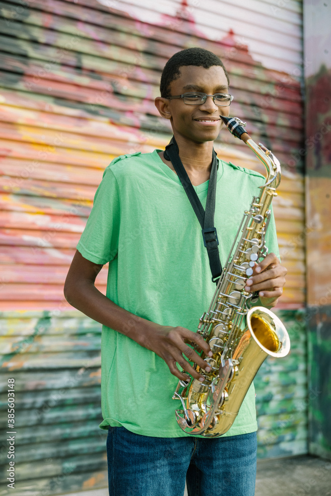 Talented Black teenager practicing saxophone at school on colorful ...