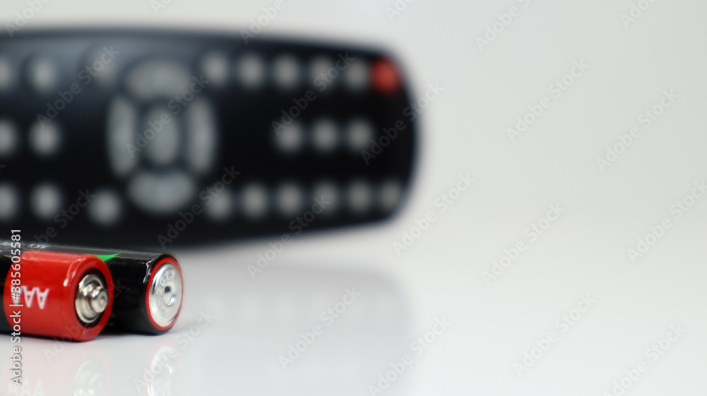 Black TV remote control with AAA alkaline batteries in red and white on ...