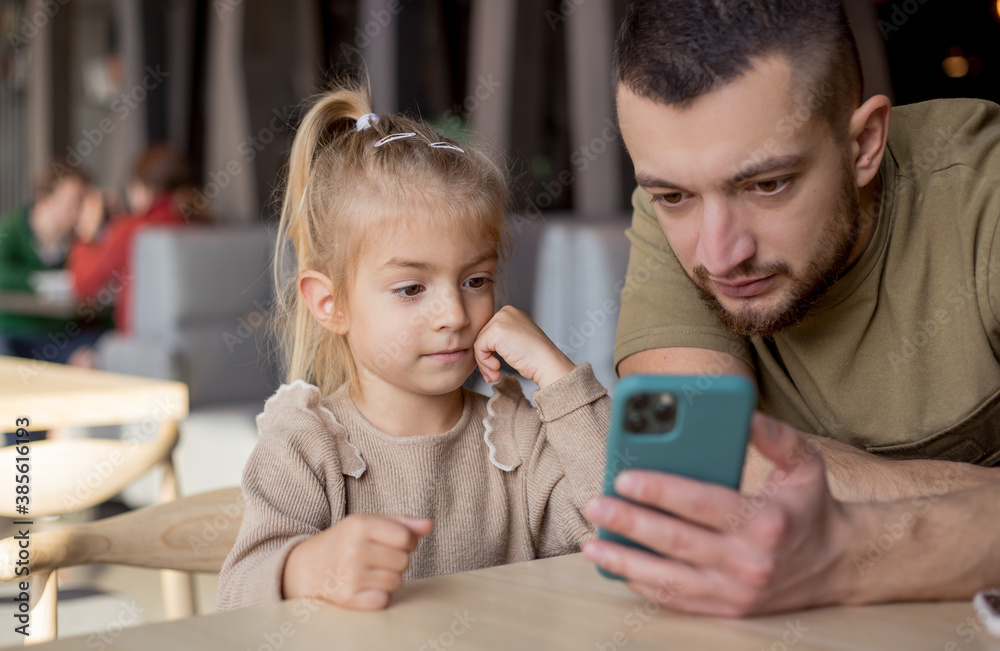 Young daddy embracing child daughter, showing funny videos on ...