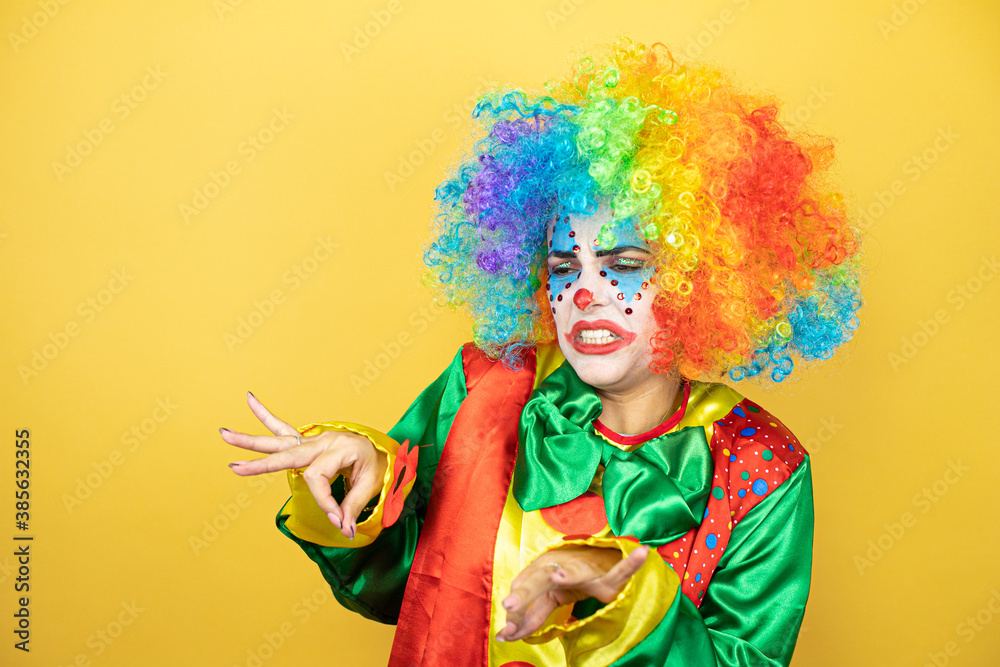 Clown standing over yellow insolated yellow background disgusted ...