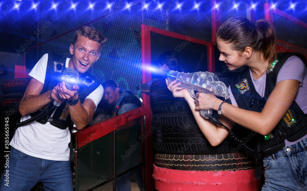 Young guy holding colored laser guns and took aim during laser tag game ...