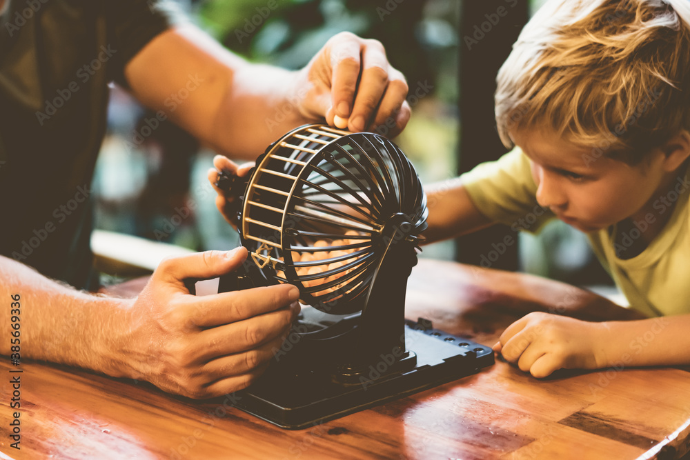 Father blond son boy play lotto, round sphere spins with small orange ...