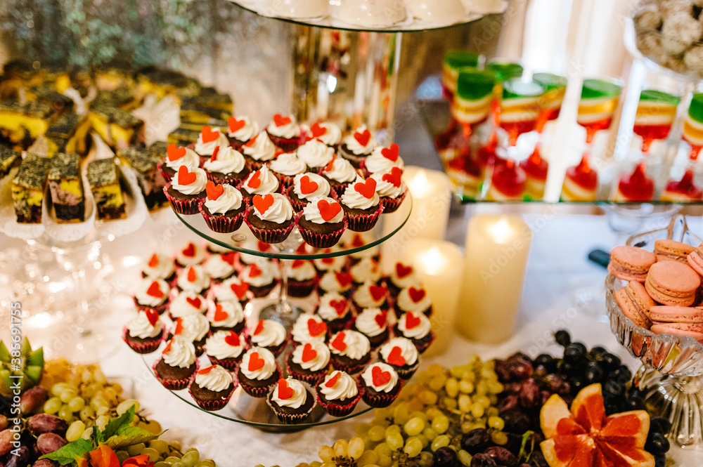 Colorful table with sweets and goodies for the wedding party reception decorated dessert table. Delicious sweets on candy buffet. Dessert table for a party. cakes cupcakes. Stock Adobe Stock
