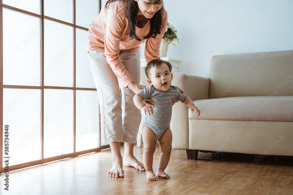 baby first step walking. mother help her baby to walk her first step at ...