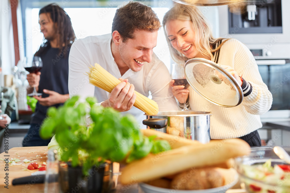 Happy friends cook spaghetti pasta together in kitchen for lunch Stock ...