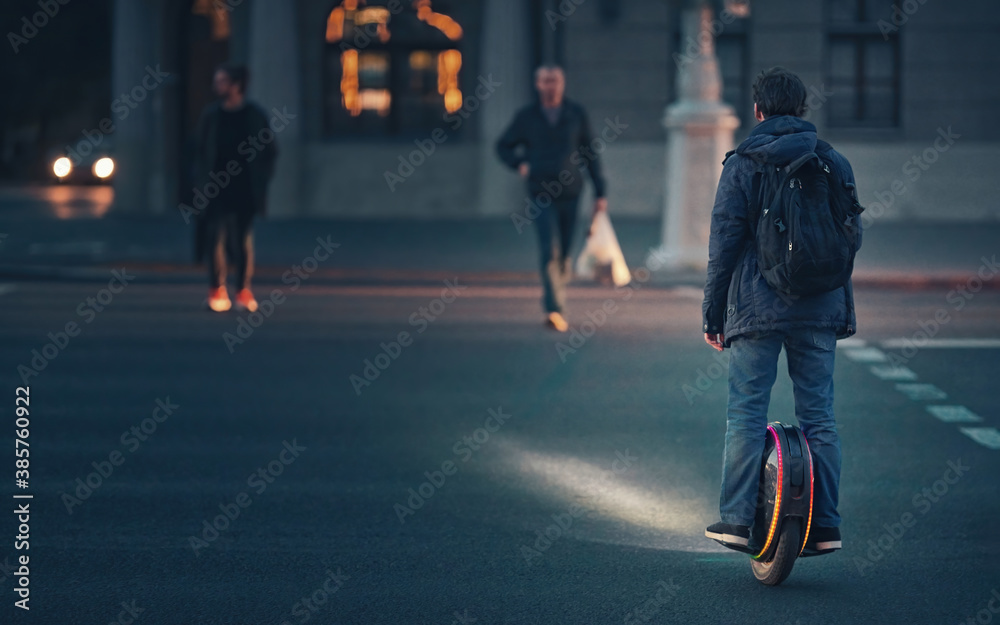 Man riding fast on electric unicycle through crosswalk at night with ...
