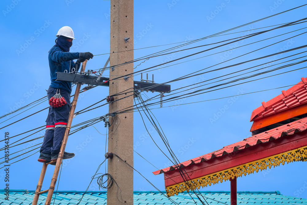 Asian technician on wooden ladder is installing cable lines to connect ...