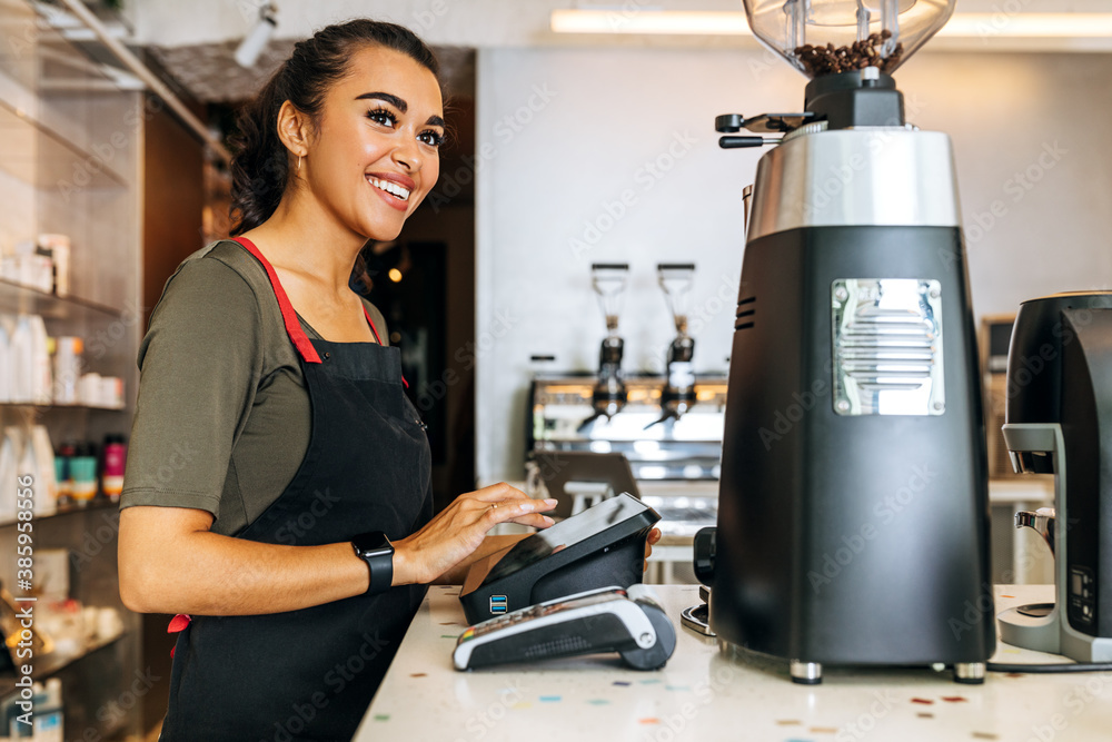 Female barista at counter using cashbox computer in coffee shop ...