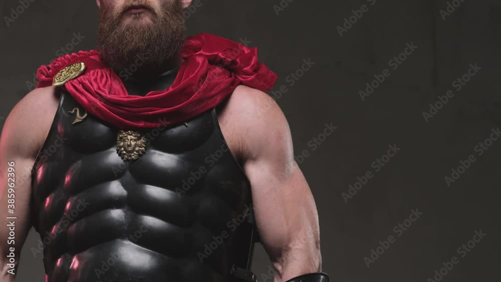 Warlike and bearded rome warrior with black armour and red cape posing ...