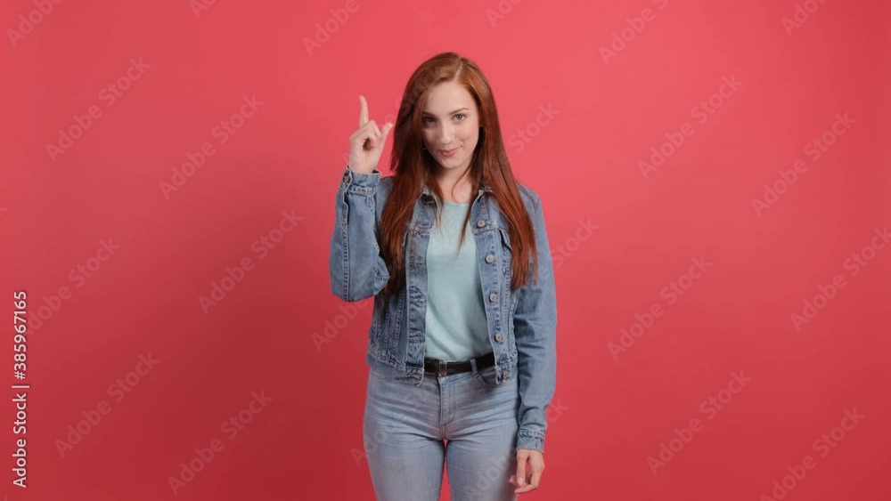 Young woman on red background showing and raising a finger as a sign of ...