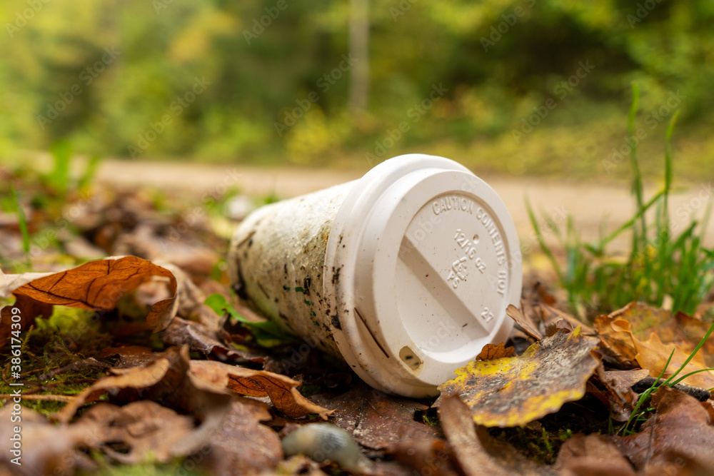 Old disposable coffee cup in the forest next to the road. Plastic ...