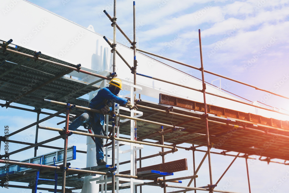 Workers on high install scaffolding, stage on board in shipyard during ...