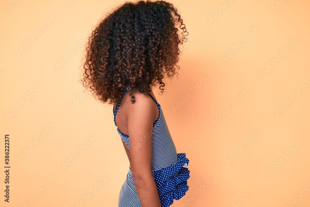 African american child with curly hair wearing swimwear looking to side ...