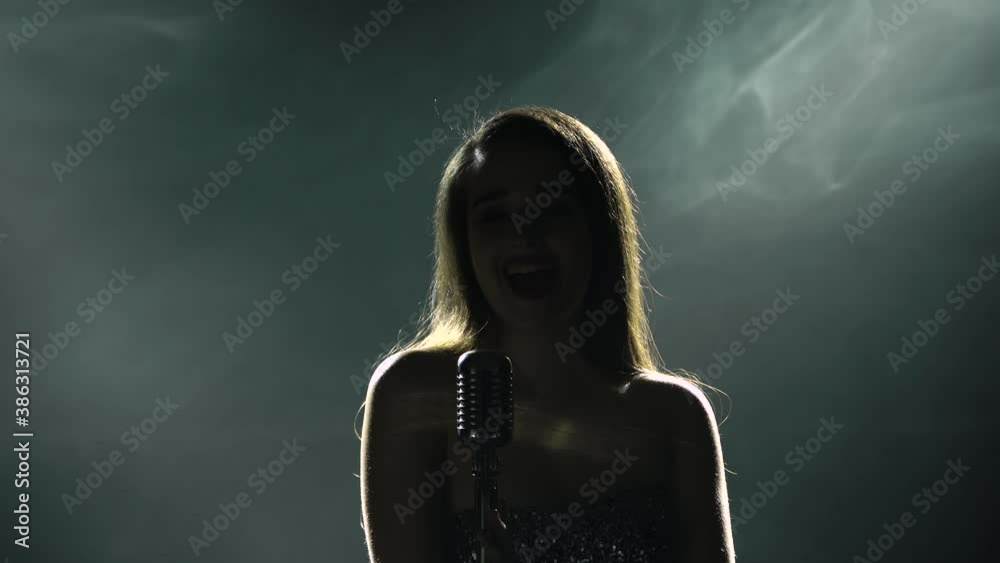 Singing woman artist in a shiny dress on stage. A close-up of the ...