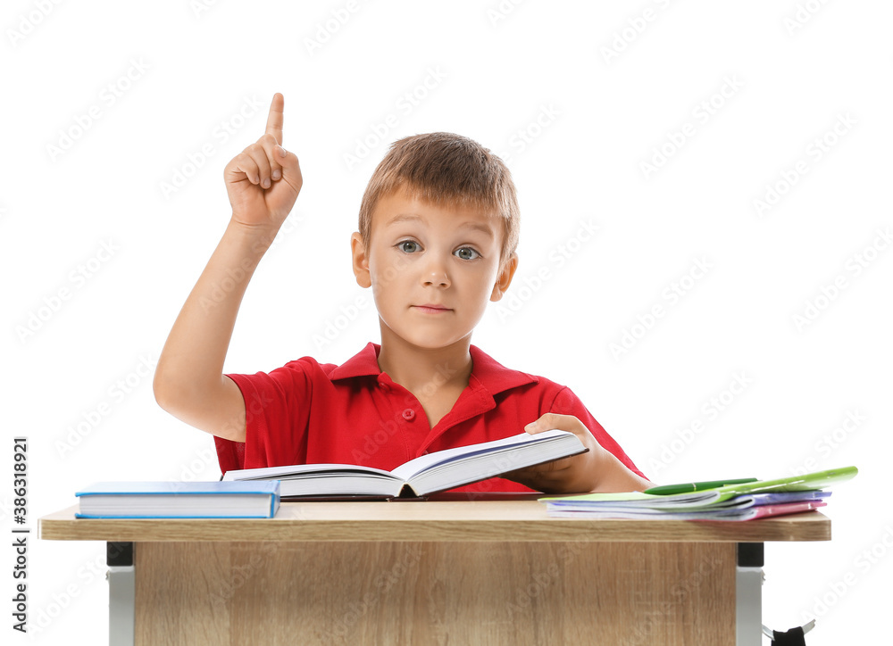 Little pupil with raised index finger sitting at school desk against ...