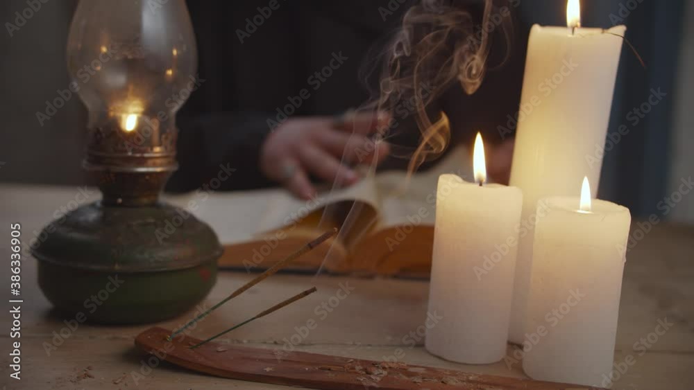 Foreground burning candles and incense sticks placing on rustic table ...