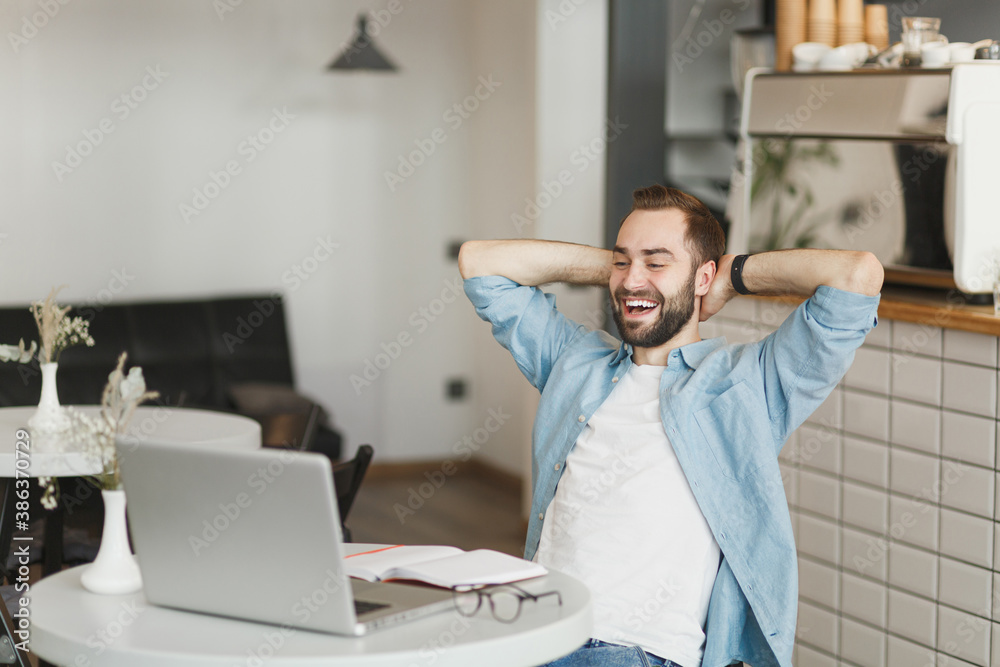 Cheerful young man sitting alone at table in coffee shop cafe ...