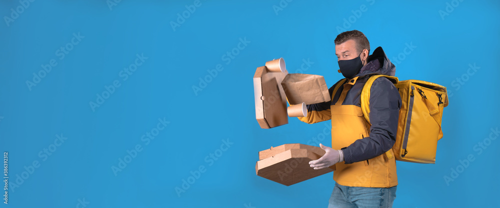 Food delivery man in yellow uniform, wearing mask and gloves, slipped ...
