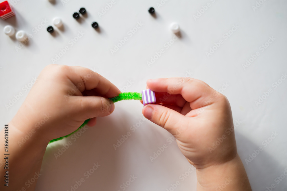 child stringing beads on string. development of baby's fine motor ...