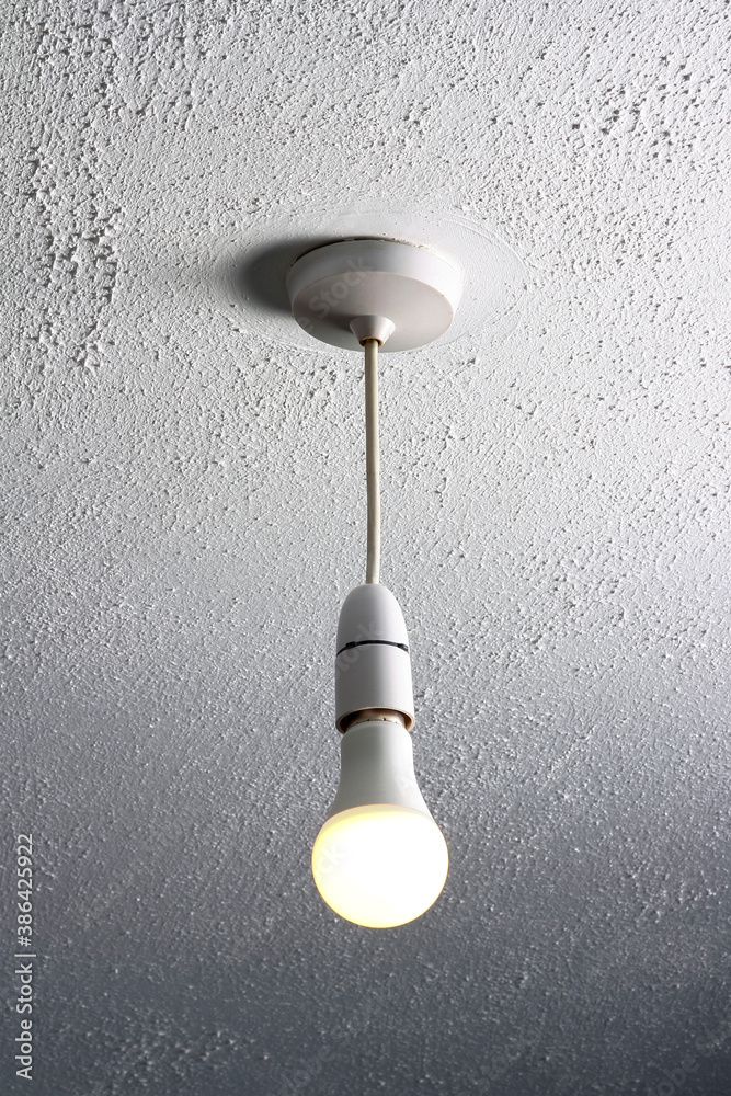 UK pendant light fitting with LED bulb fixed to a textured ceiling foto ...