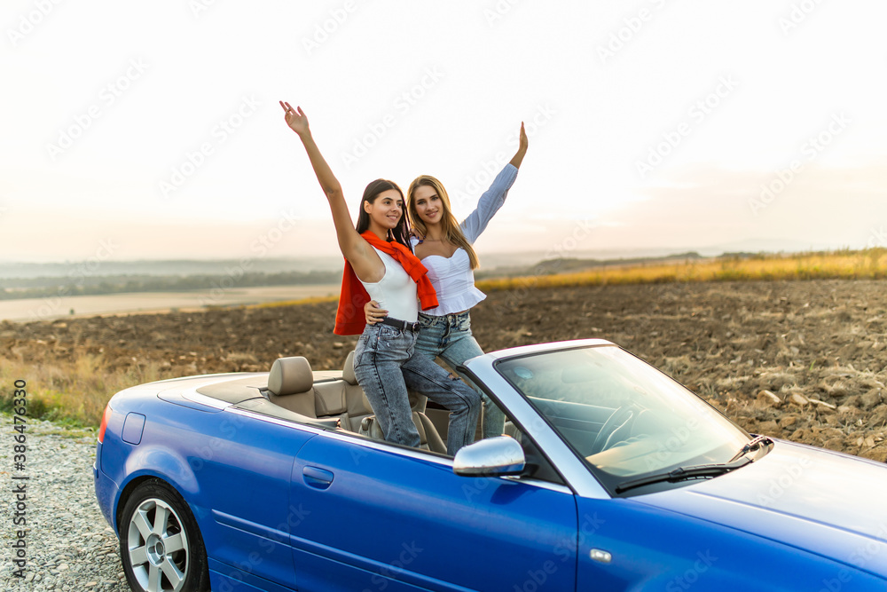 Happy two women in car driving on road trip. Young two women having fun ...