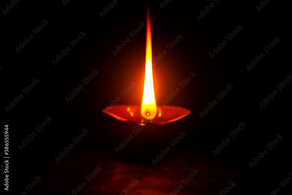 Diwali Diya in black. Deepam oil lamp. Flame in dark. a light powered ...