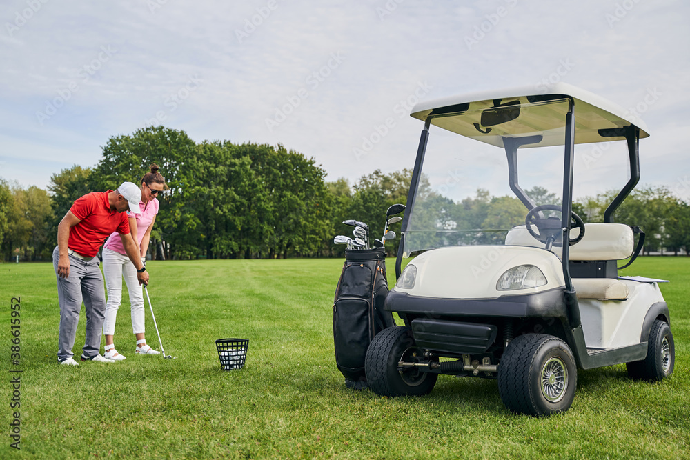 Woman striking the golf ball with a putter Stock Photo | Adobe Stock