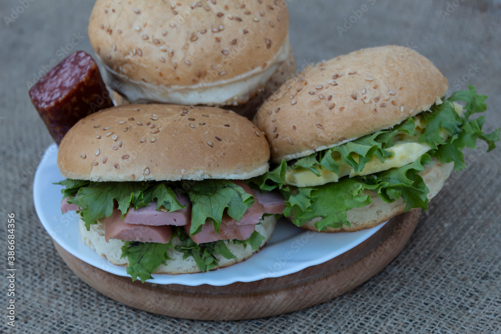 On a round board is a plate with two sausage, cheese and salad ...
