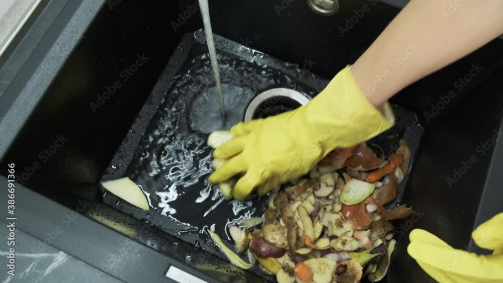 Vegetable and fruit waste in the kitchen sink. Woman using a food ...