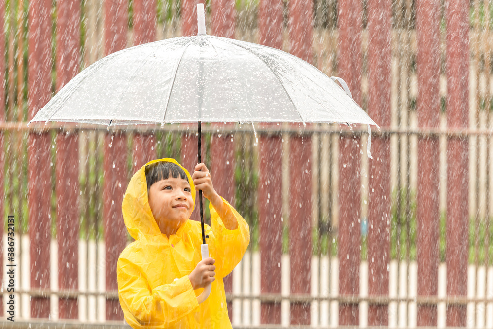 Happy asian little child holding an umbrella having fun to playing with ...