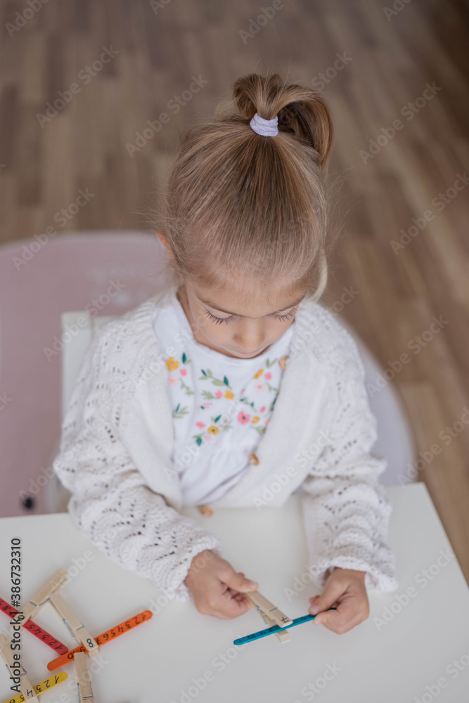 Little girl learning numbers with colourful sticks and clothespins ...