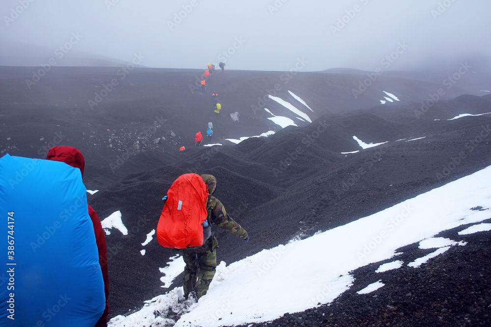 A group of tourists overcomes a difficult mountain pass, fog and rain ...