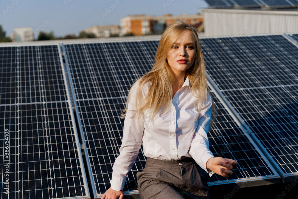 Girl and solar panels stands in row on the ground at sunset. Woman ...