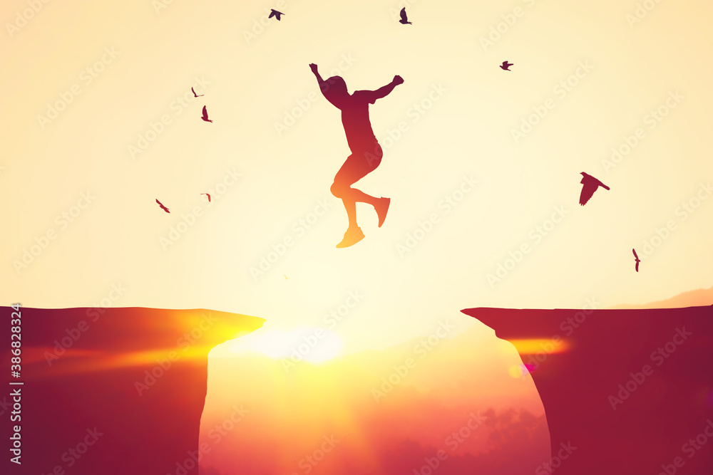 Silhouette man jumping between cliff at top of mountain background with ... Silhouette man jumping between cliff at top of mountain background with ...