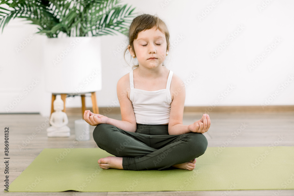Little pretty child girl relaxes with her eyes closed in a yoga lotus ...