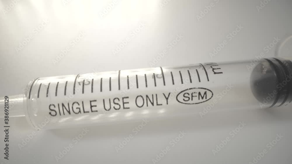 An empty unused syringe is on a white table without a needle. It says ...