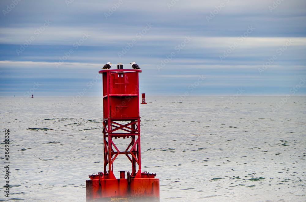Red metal buoy swimming on ocean floating at sea with dramatic sky ...