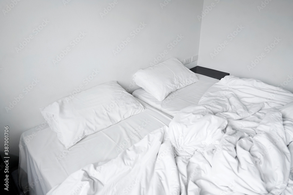 Messy pillow and blanket on bed in white room. Lazy and relax days ...