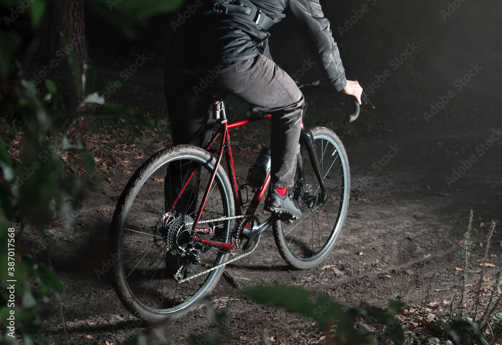 Foto de Cyclist on a forest trail at night. Man on bicycle in the dark ...