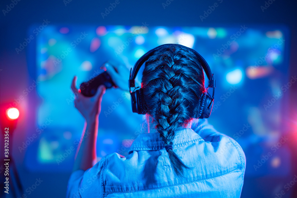 View from back of beautiful gamer woman playing video game at home in ...