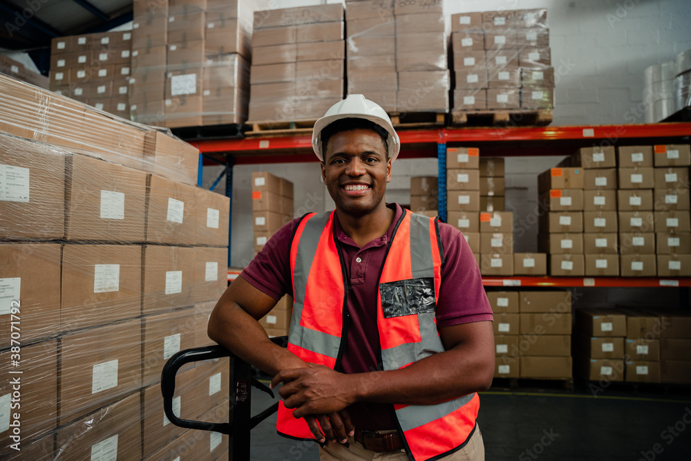 Male factory worker smiling besides packages in warehouse Stock Photo ...