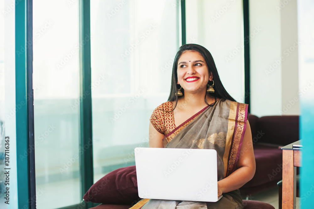 Inspired beautiful Indian young woman in a saree using her laptop ...